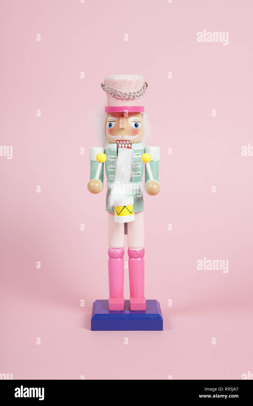 wood nutcracker figurine placed on a pink background. Color harmony ...