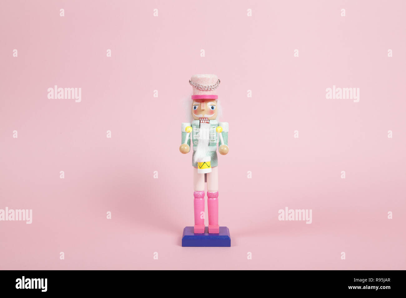 wood nutcracker figurine placed on a pink background. Color harmony ...