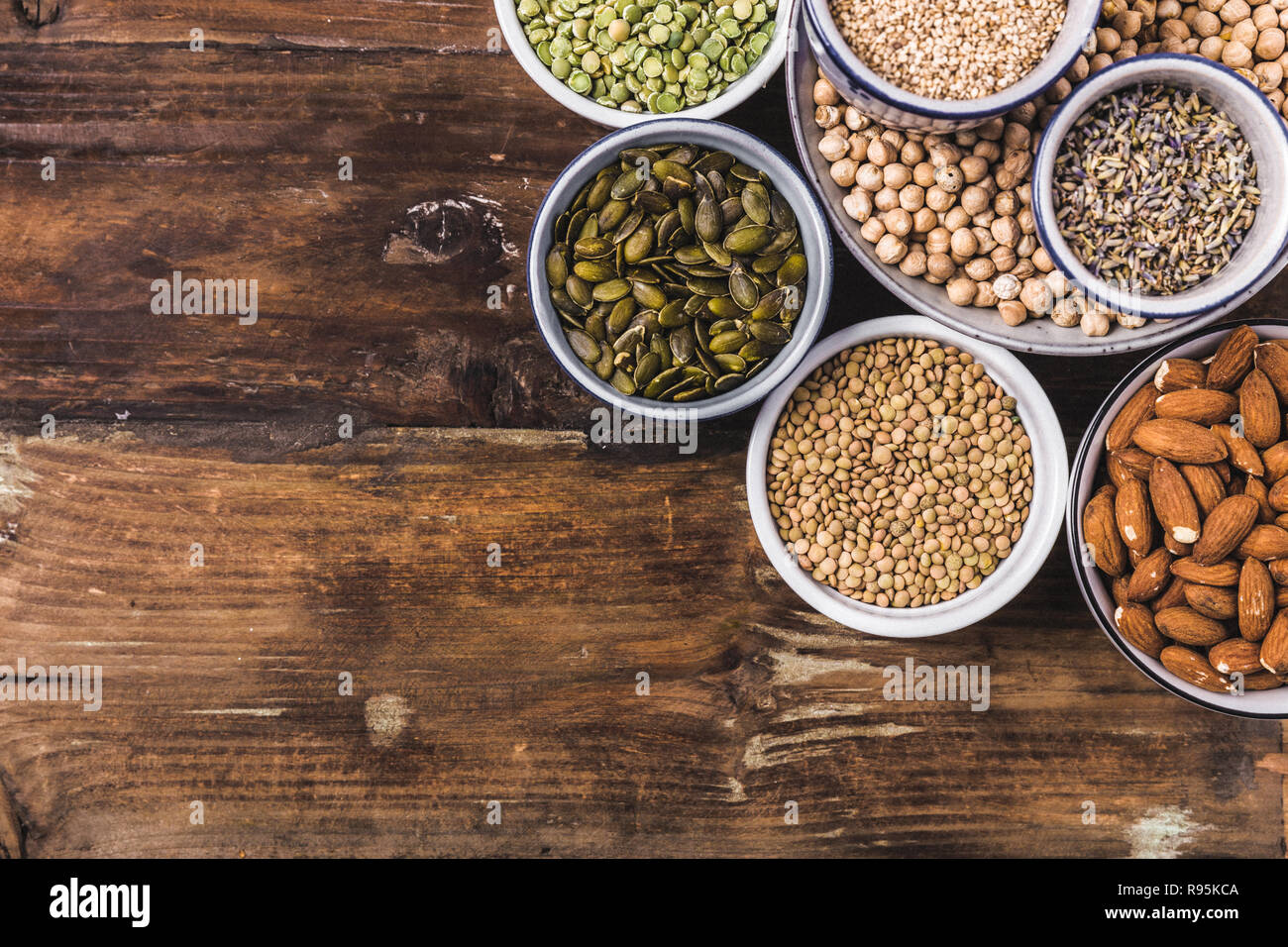 Composition of different types of legumes in bowls on wooden background ...