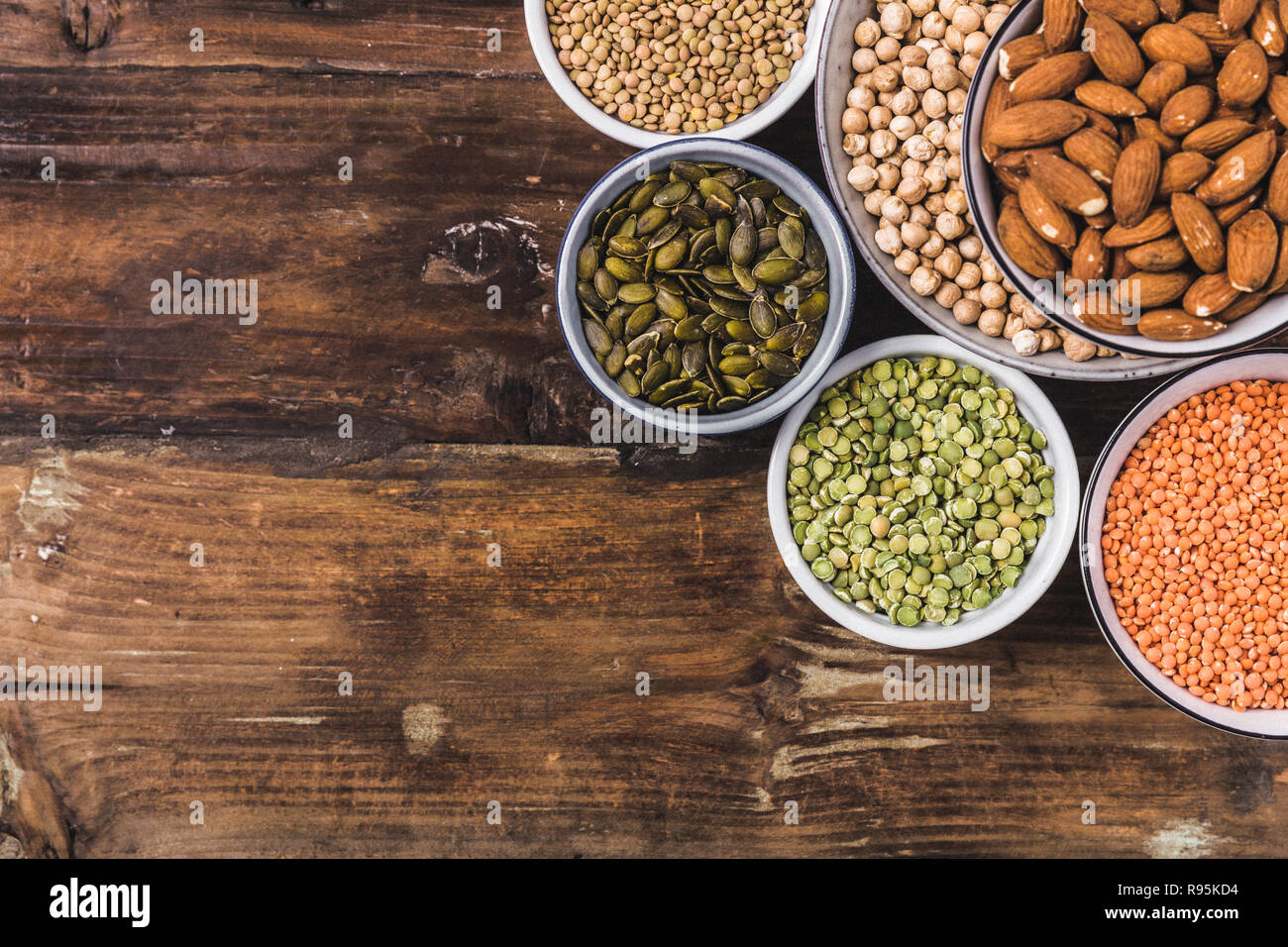 Composition of different types of legumes in bowls on wooden background ...