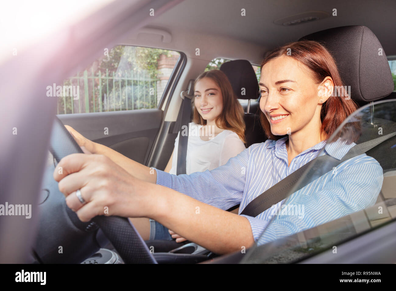 Side view portrait of female driver and girl passenger during road trip ...