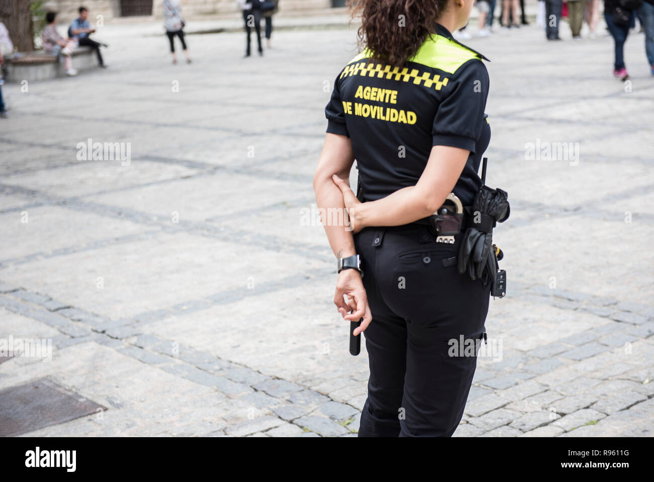 A female policewoman standing alert on duty wearing her uniform. She is ...