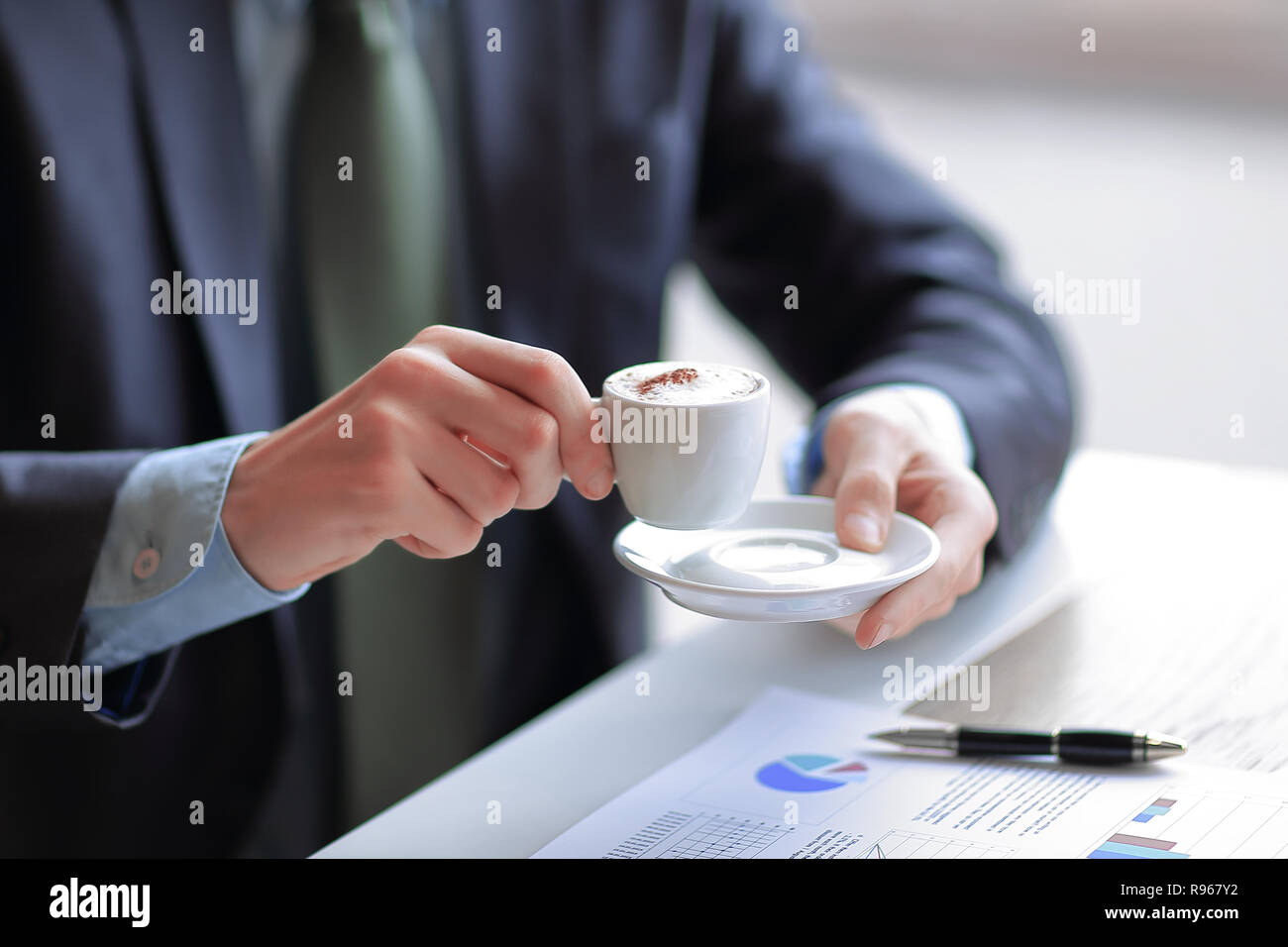 closeup of a young businessman with a cup of coffee in his hand checks ...