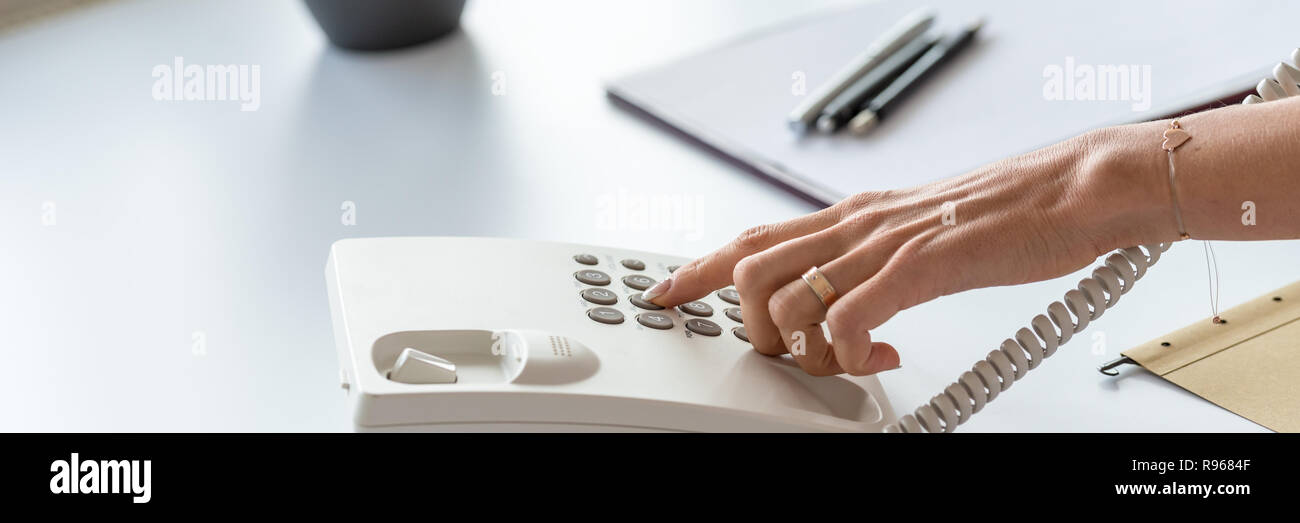 Wide view image of hand of a female secretary dialing a telephone ...