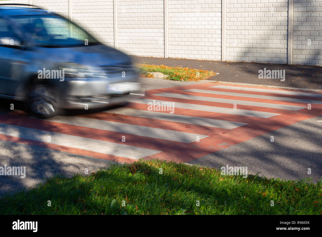 Car crossing passing a dangerous crosswalk marked with red. Blurred ...
