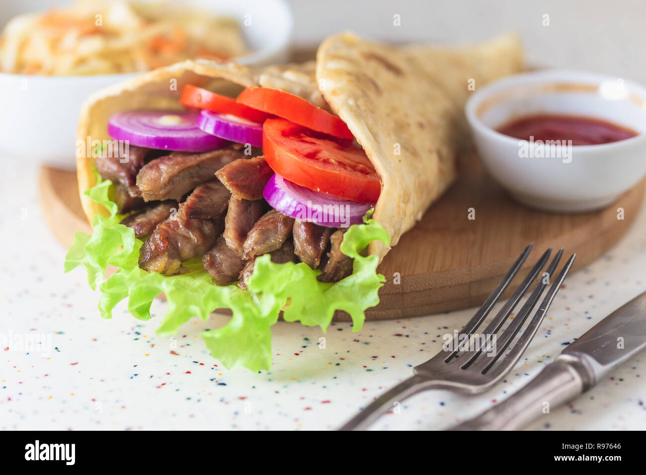 Handmade doner kebab is lying on the white table made of artificial ...