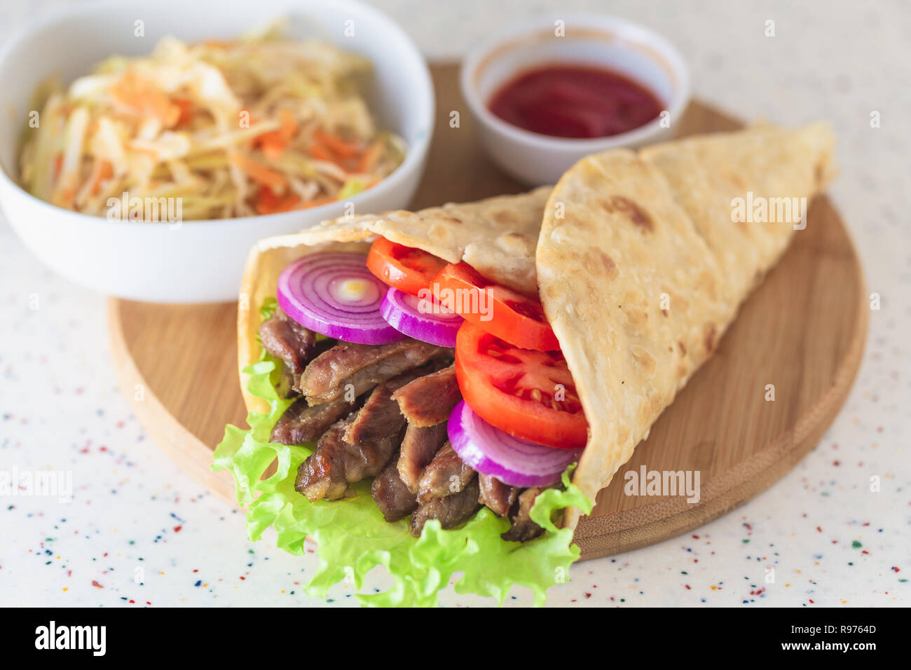 Handmade doner kebab is lying on the white table made of artificial ...