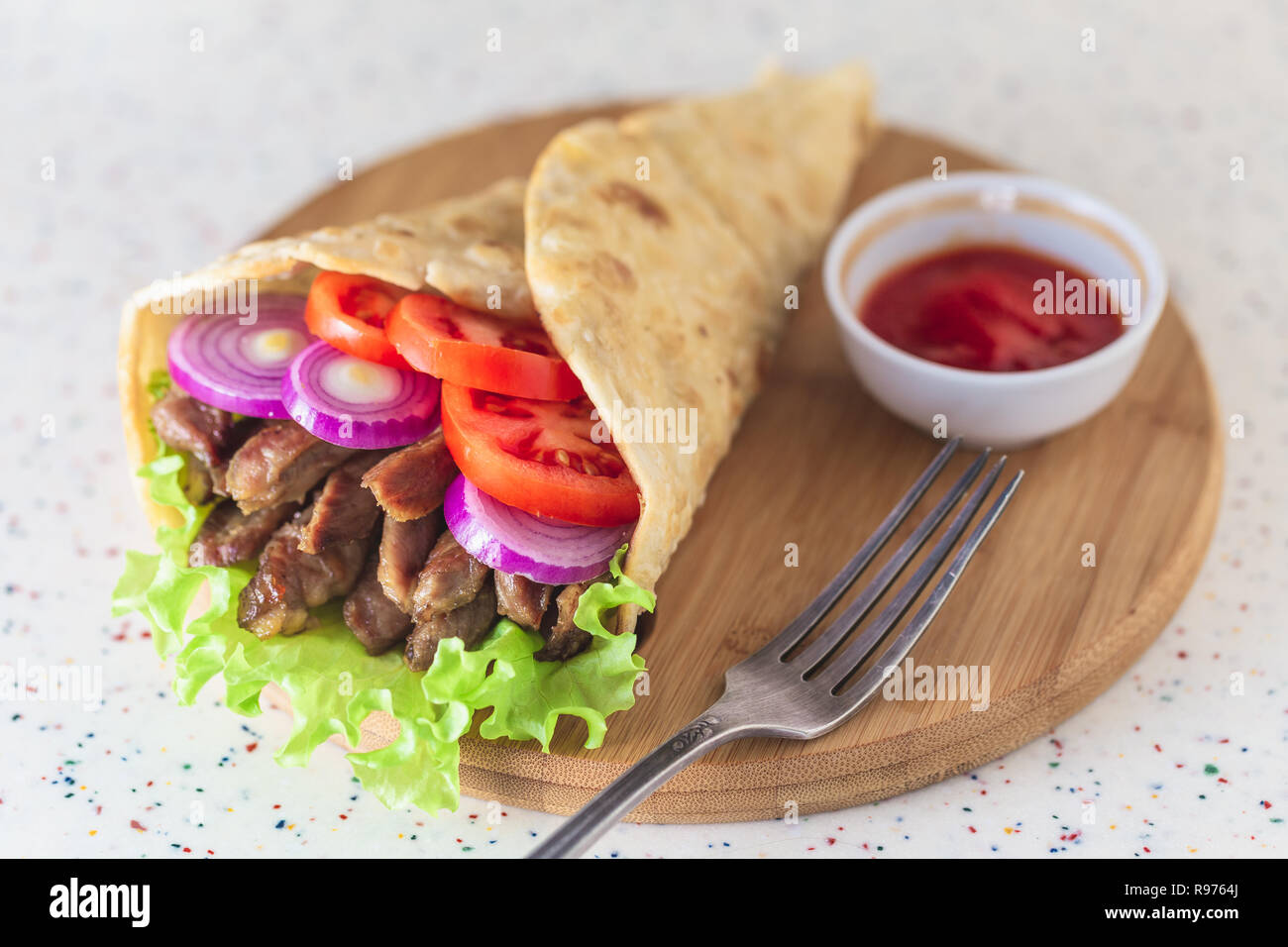 Handmade doner kebab is lying on the white table made of artificial ...