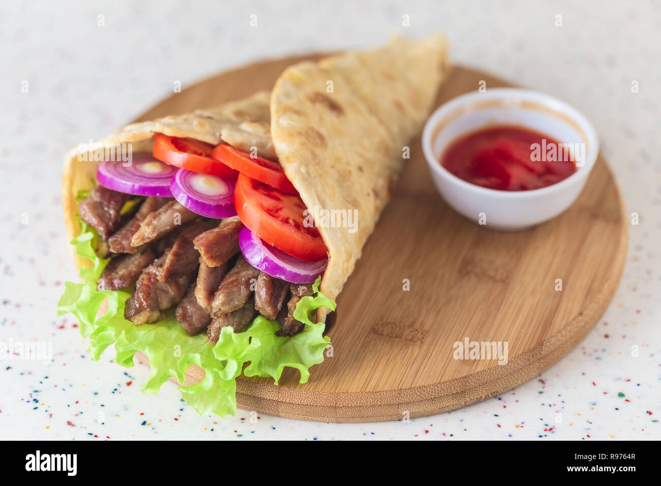 Handmade doner kebab is lying on the white table made of artificial ...
