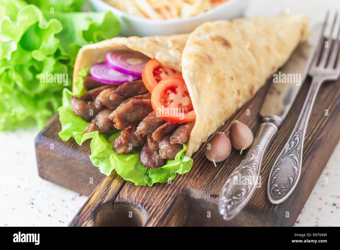 Handmade doner kebab is lying on the white table made of artificial ...
