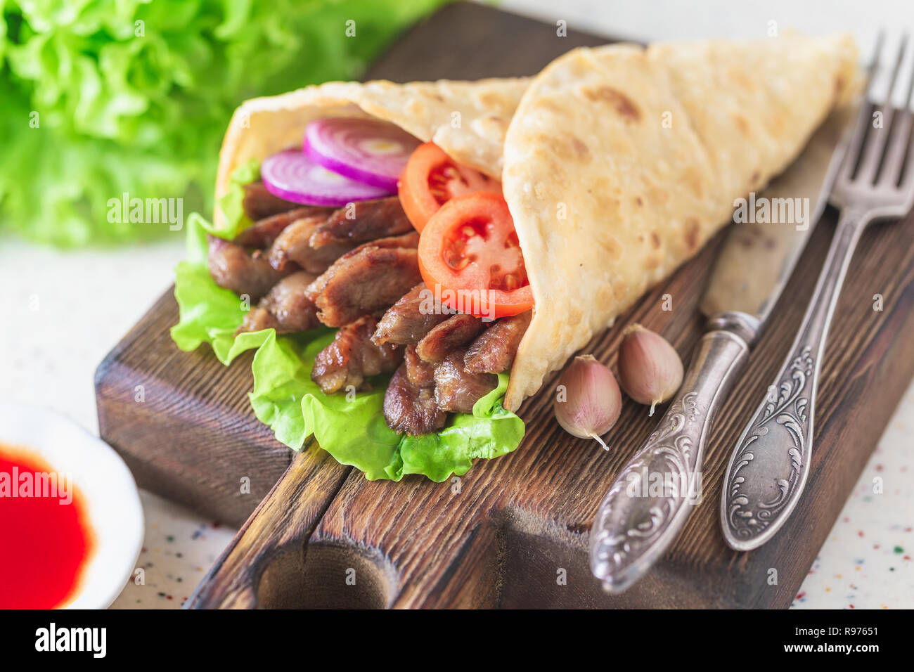 Handmade doner kebab is lying on the white table made of artificial ...