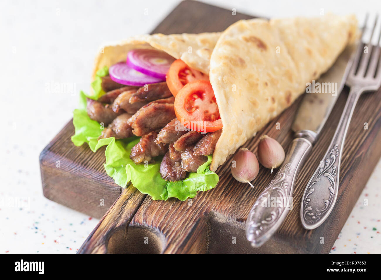 Handmade doner kebab is lying on the white table made of artificial ...