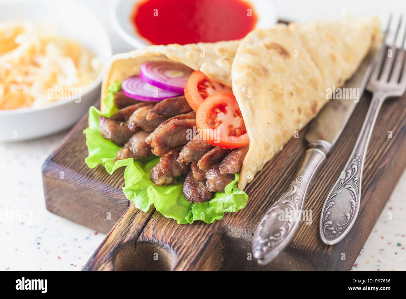 Handmade doner kebab is lying on the white table made of artificial ...