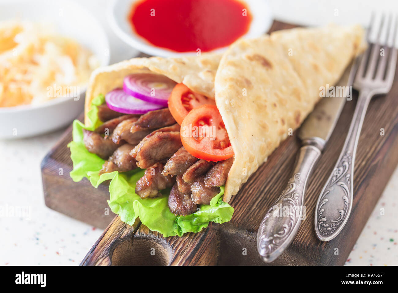Handmade doner kebab is lying on the white table made of artificial ...