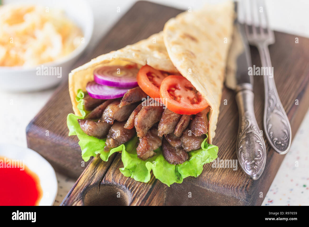 Handmade doner kebab is lying on the white table made of artificial ...