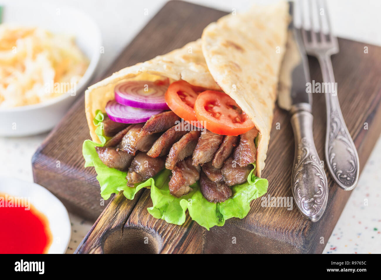 Handmade doner kebab is lying on the white table made of artificial ...