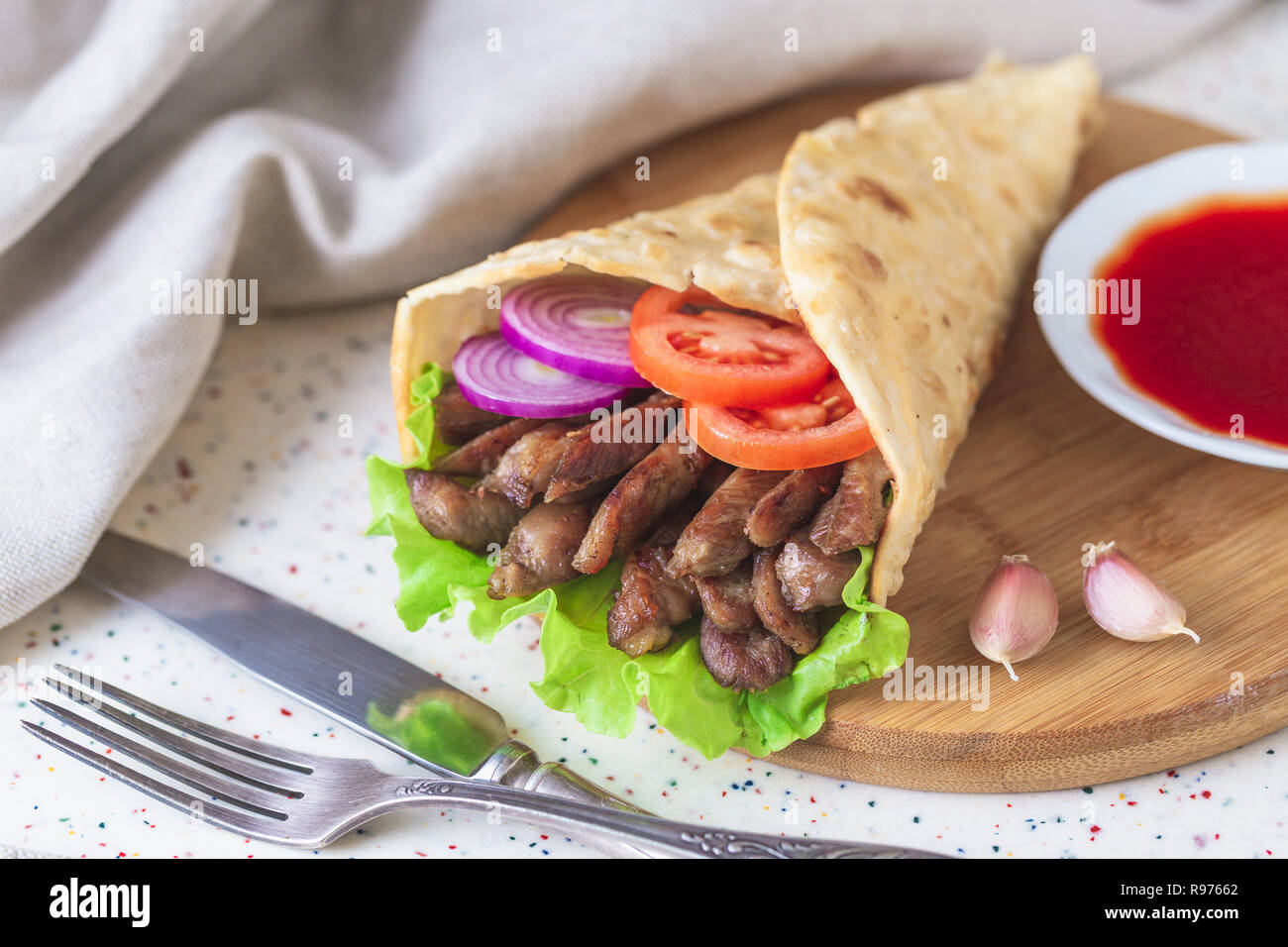 Handmade doner kebab is lying on the white table made of artificial ...