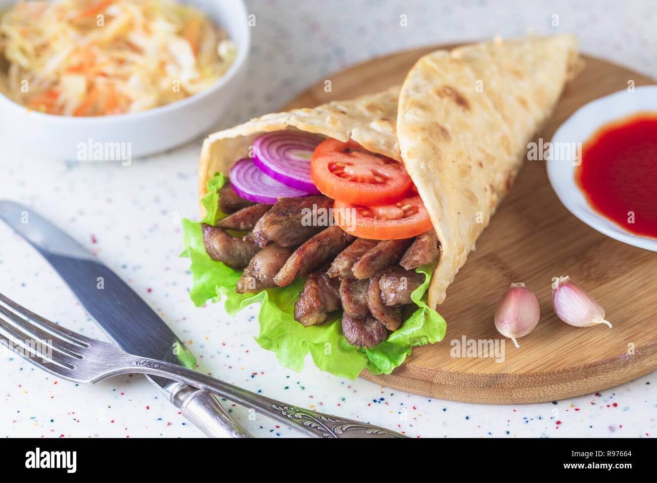 Handmade doner kebab is lying on the white table made of artificial ...