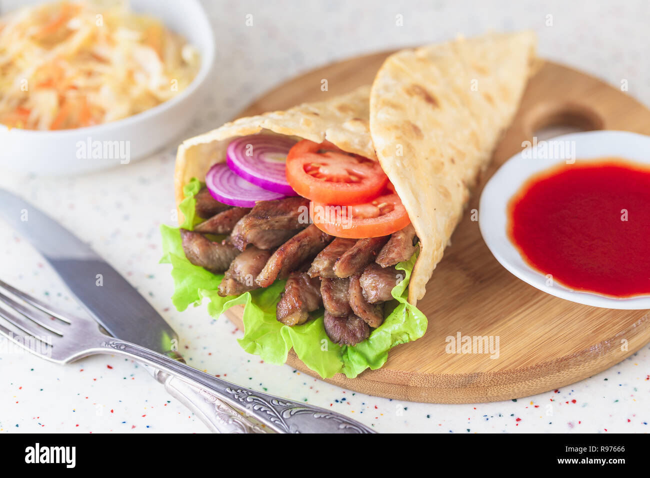 Handmade doner kebab is lying on the white table made of artificial ...