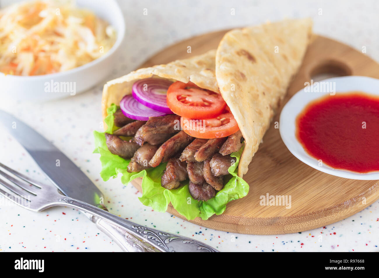 Handmade doner kebab is lying on the white table made of artificial ...