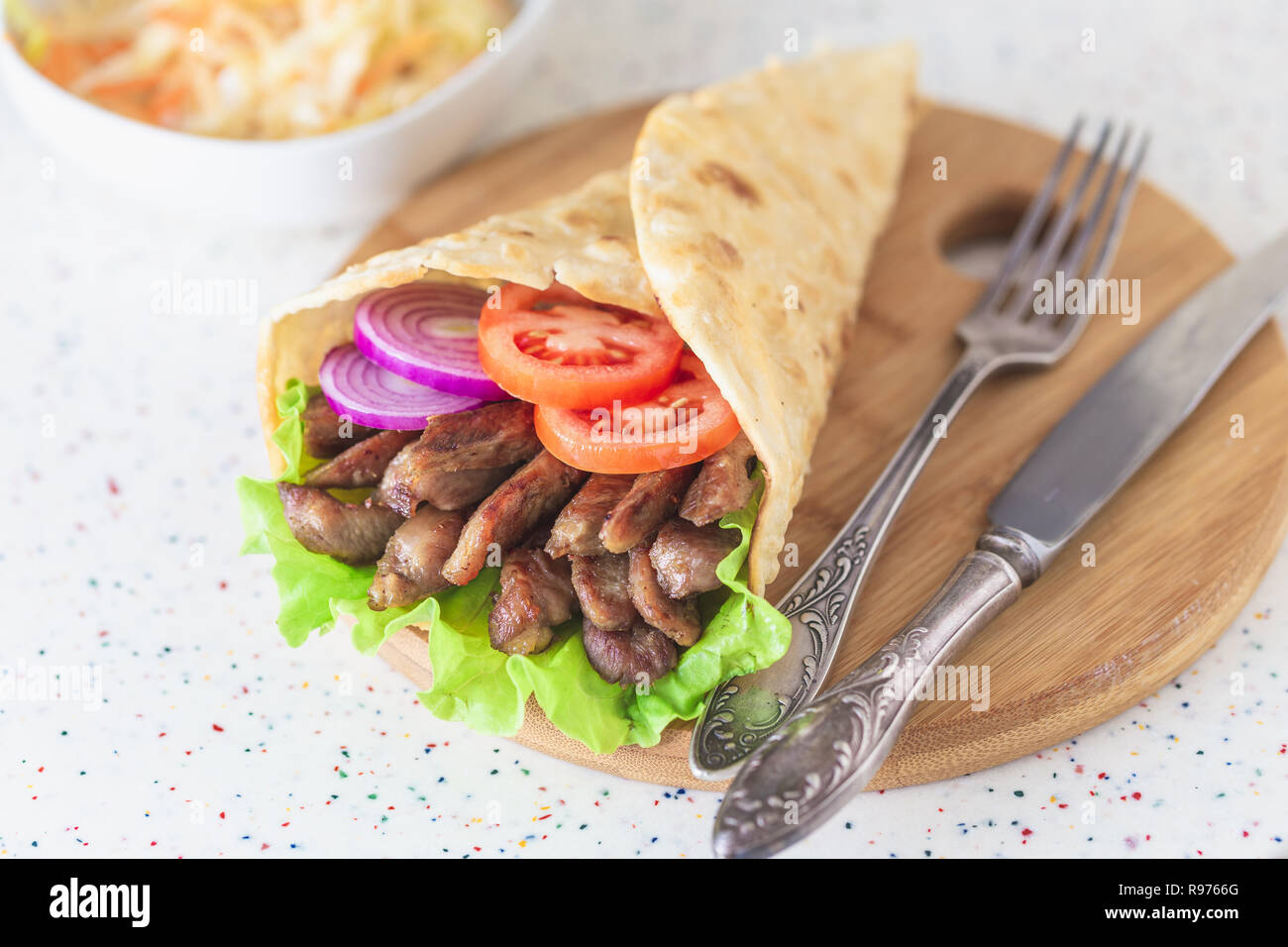 Handmade doner kebab is lying on the white table made of artificial ...