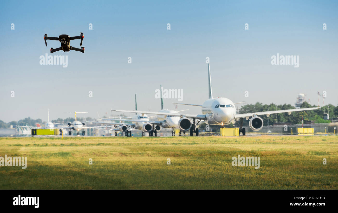 Unmanned drone flying near row of commercial airplanes at airport ...
