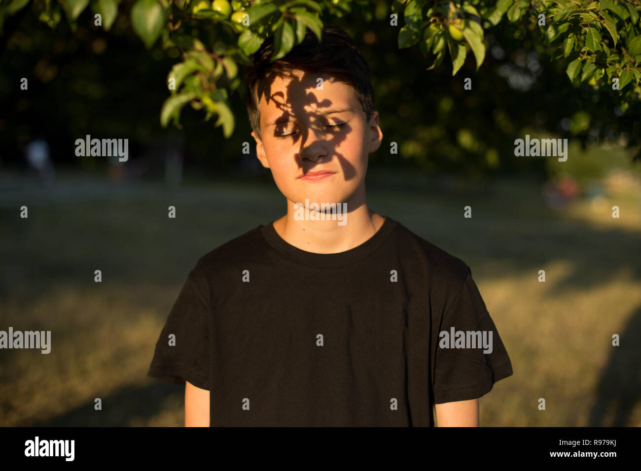 Portrait of young dreamy teen boy with eyes closed in garden. Beautiful ...