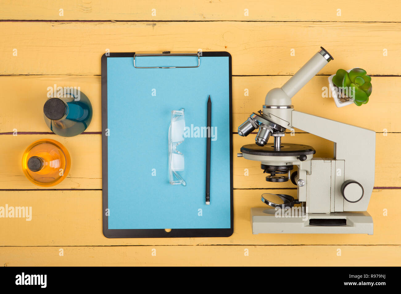 Education and science concept - microscope, blank clipboard, eyeglasses ...