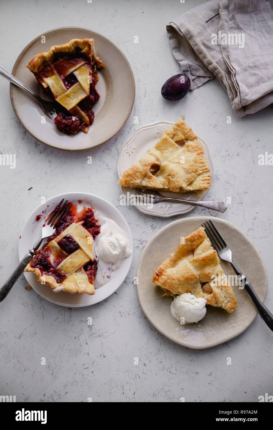 Slices of various pies in little plates. Overhead view, concrete ...