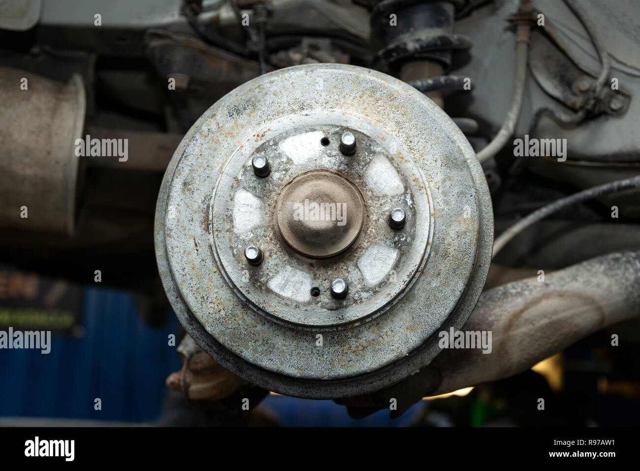 Close-up of heavily worn rear drum brakes on a car raised on a lift in ...