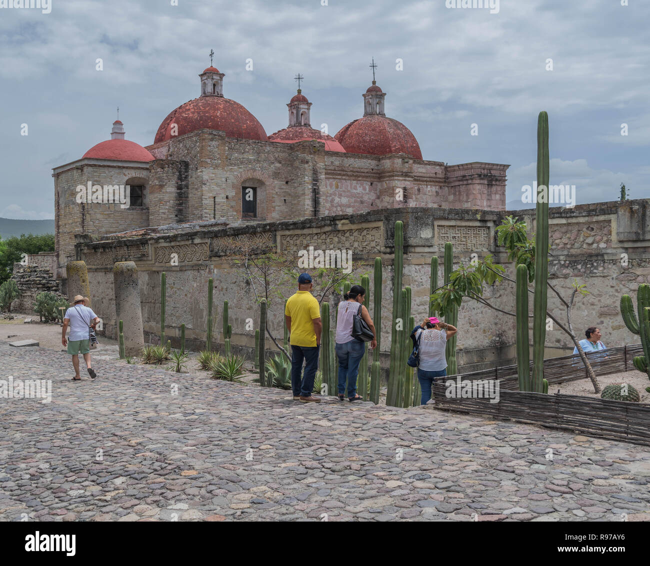 Tourist wondering around the ruins of Mitla, UNESCO World Heritage Site, with large stone church ...