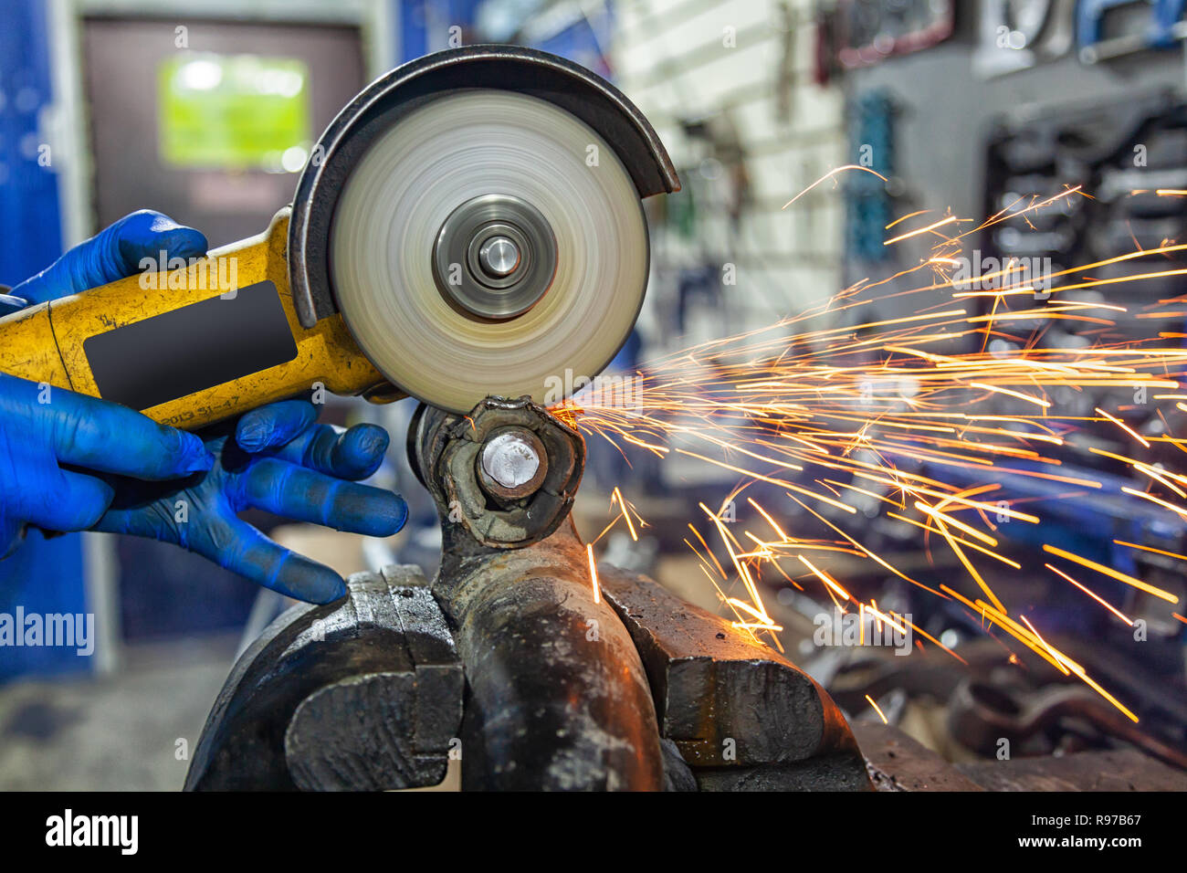 A close-up of a car mechanic using a metal grinder to cut a car silent ...