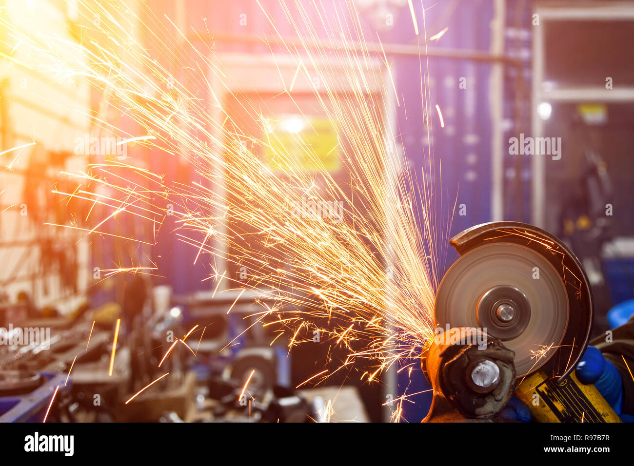 A close-up of a car mechanic using a metal grinder to cut a car silent ...
