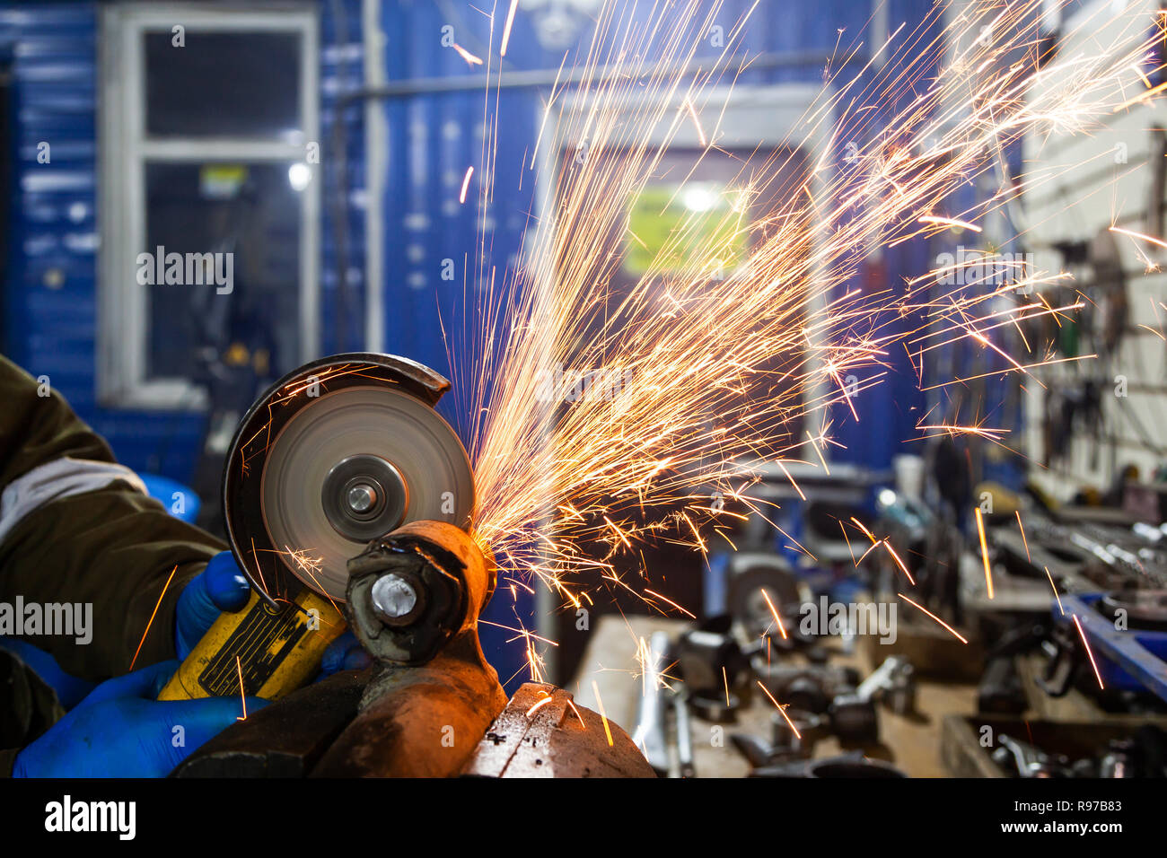 A close-up of a car mechanic using a metal grinder to cut a car silent ...