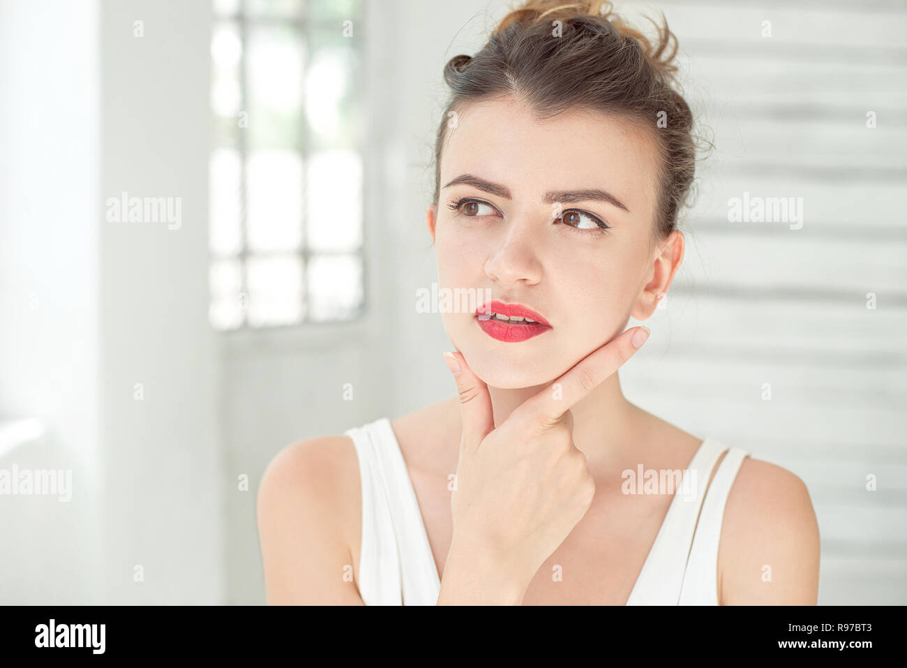 Studio portrait of beautiful young woman thinking and looking upwards ...