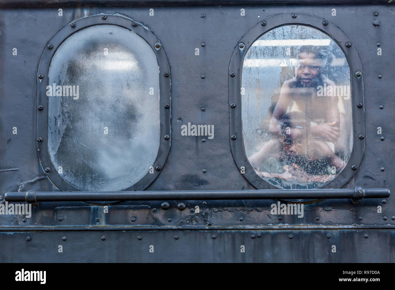 Side view of old train cabin window with reflection of two children ...