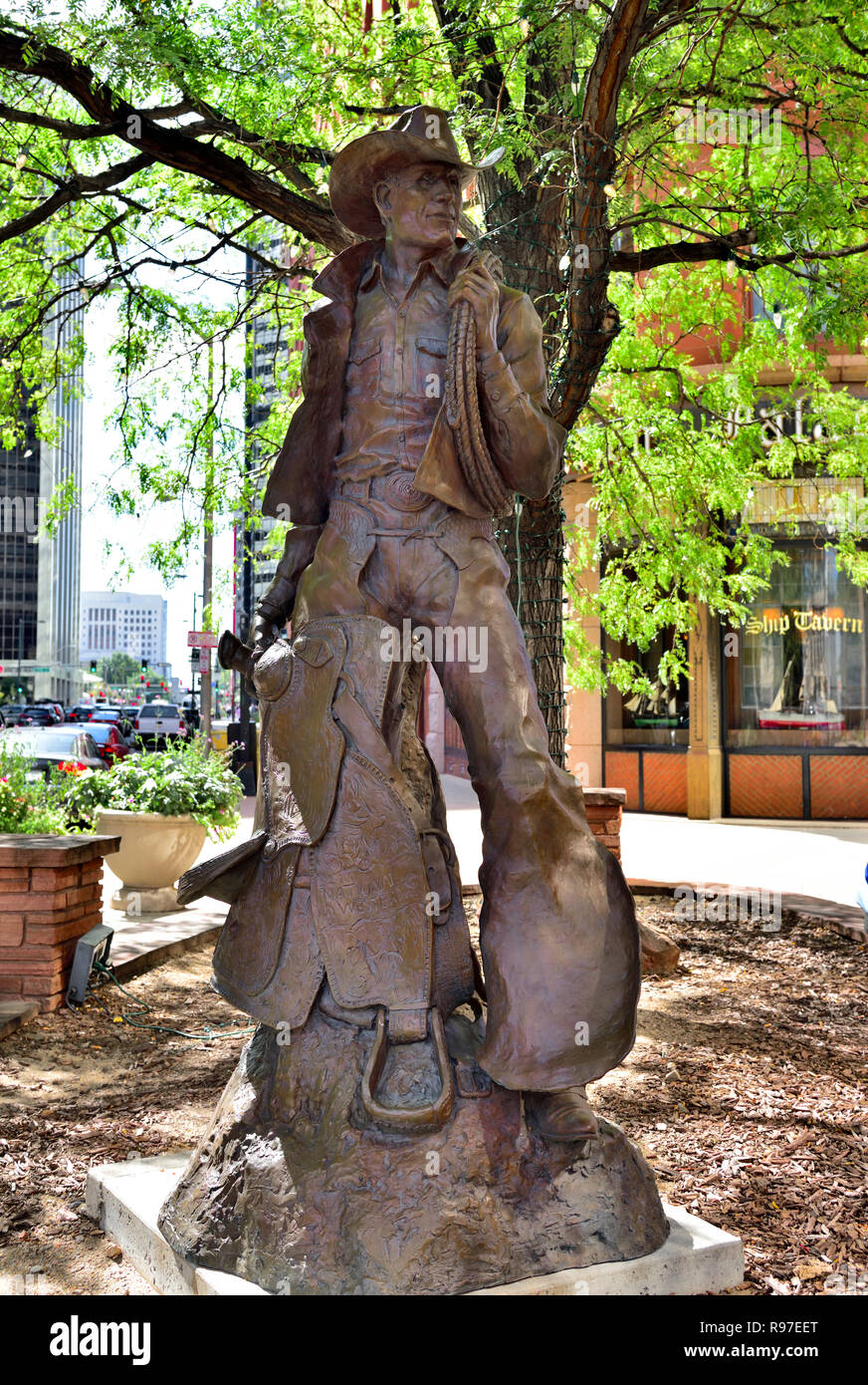 Statue of American Cowboy standing with saddle, lasso rope, chaps ...