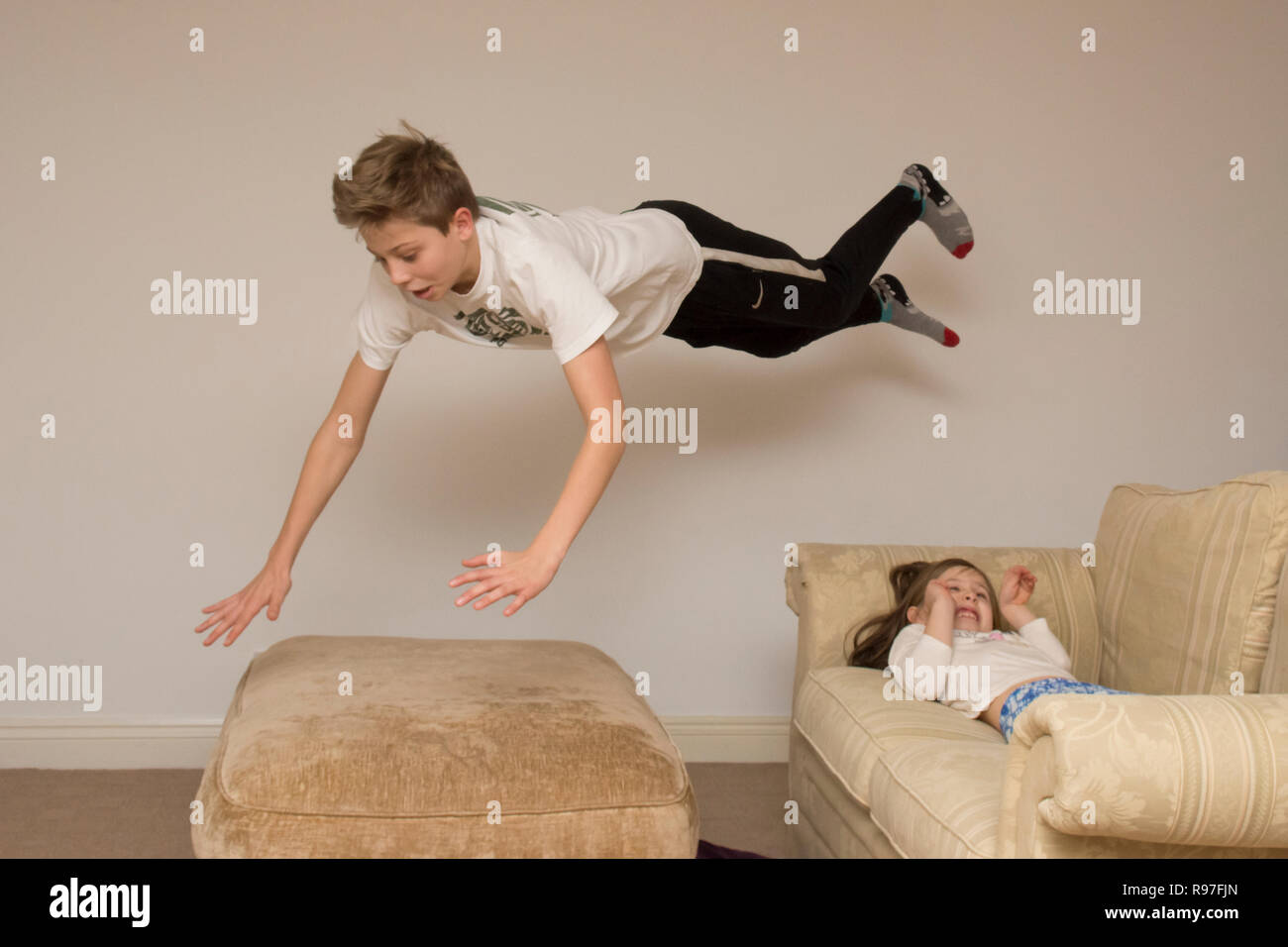 children, brother and sister jumping, diving and leaping on furniture ...