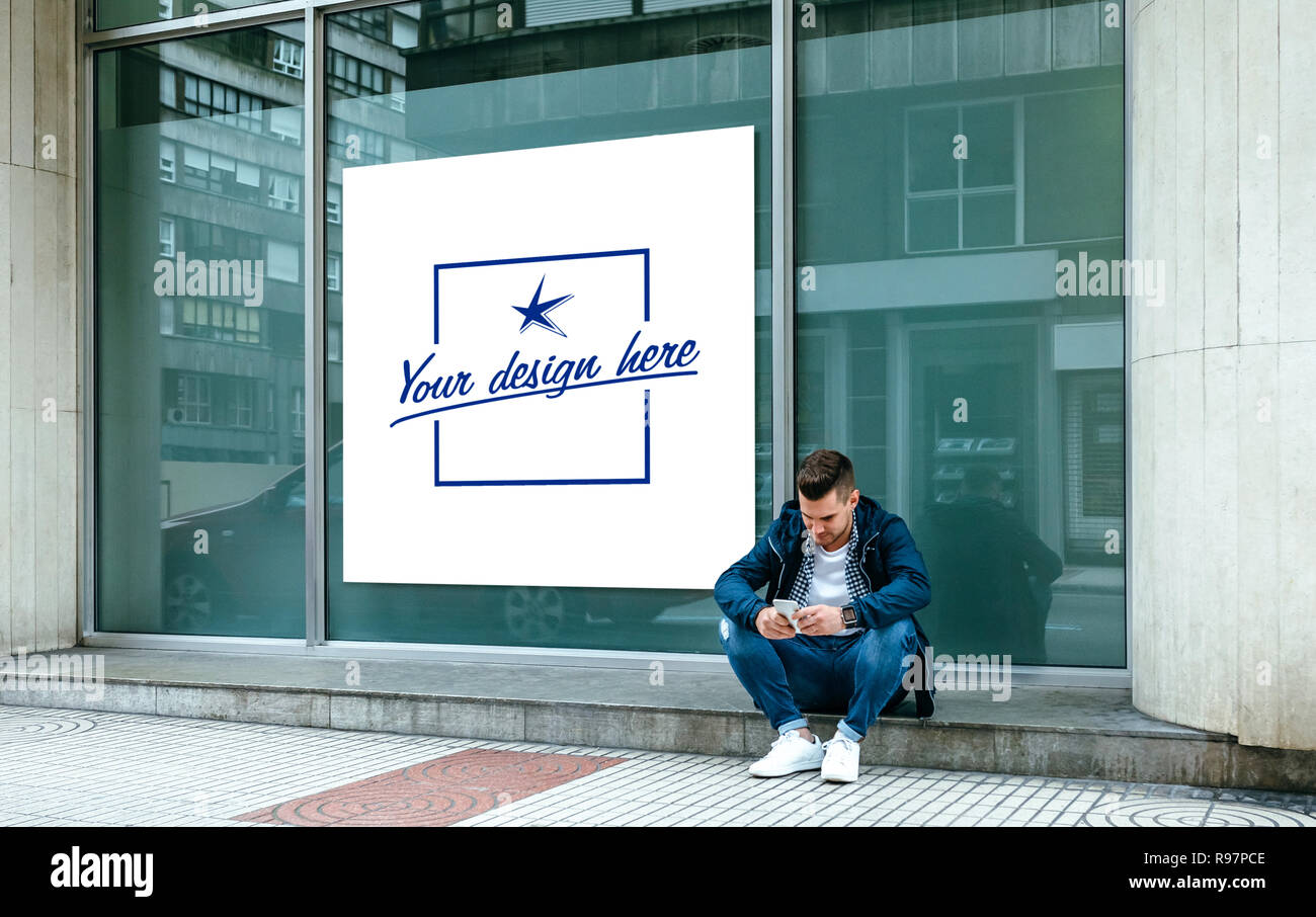 Customizable poster with a guy sitting looking mobile Stock Photo - Alamy