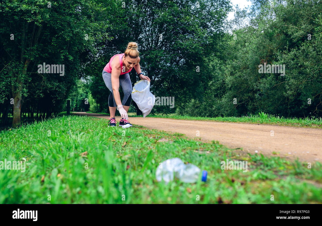 Girl picking up trash doing plogging Stock Photo - Alamy