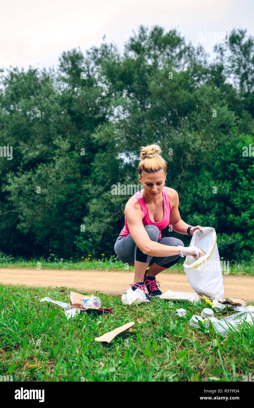 Girl picking up trash doing plogging Stock Photo - Alamy