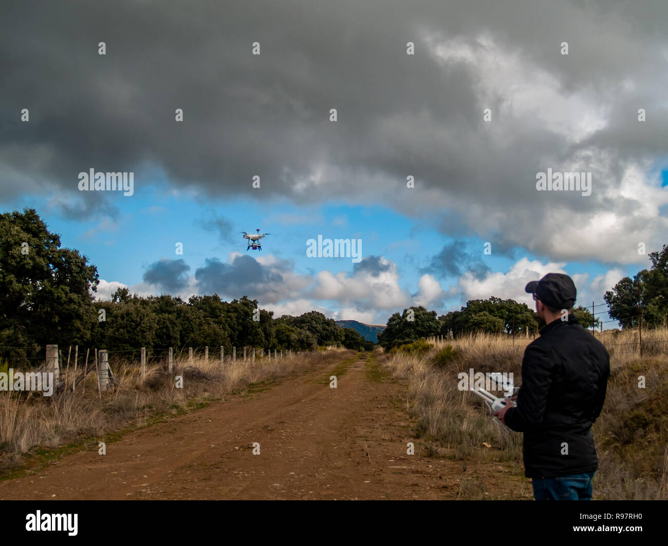 A drone pilot piloting with the remote control with smartphone in his ...
