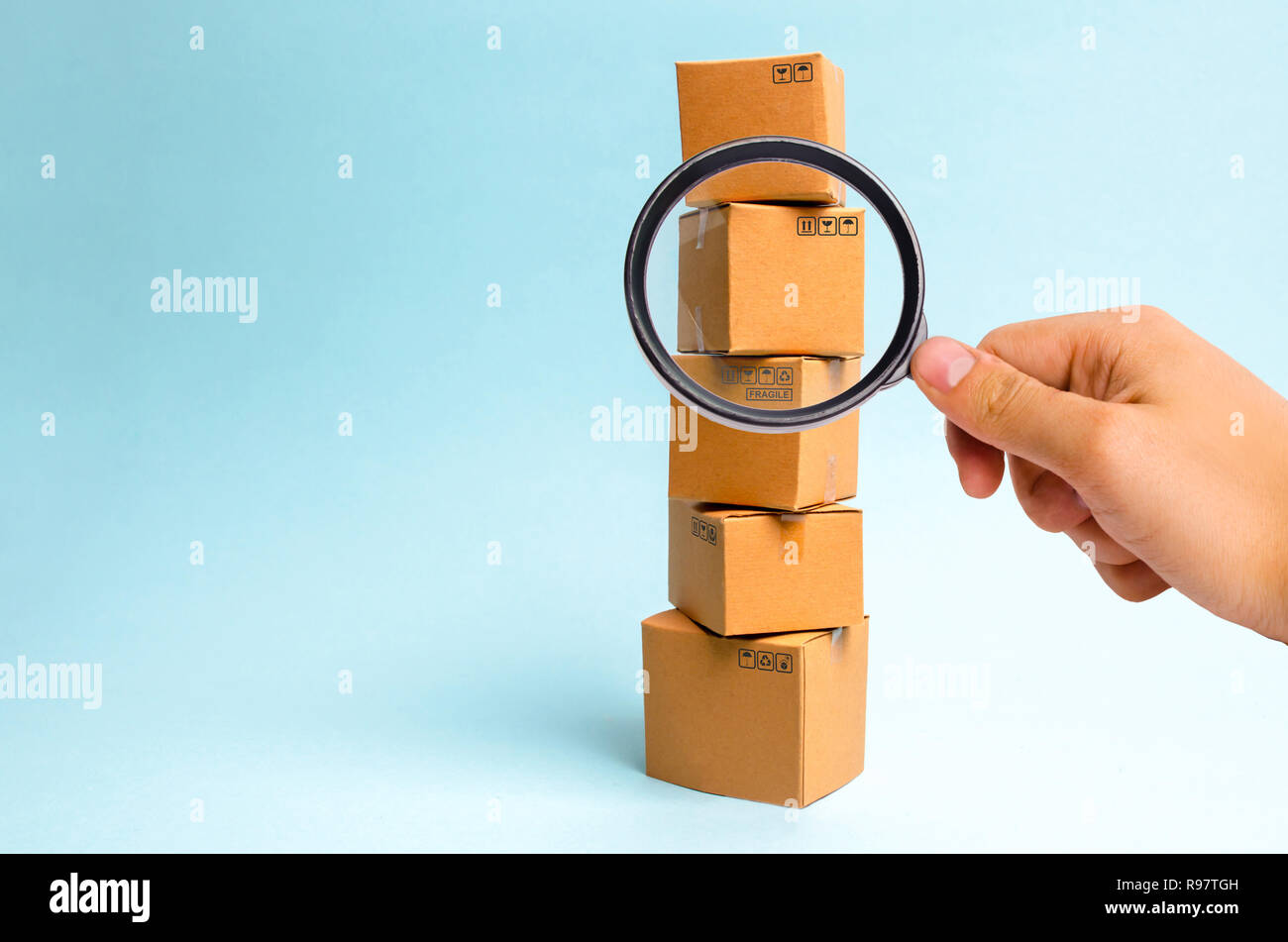 Magnifying glass is looking at the Tower of cardboard boxes on a blue ...