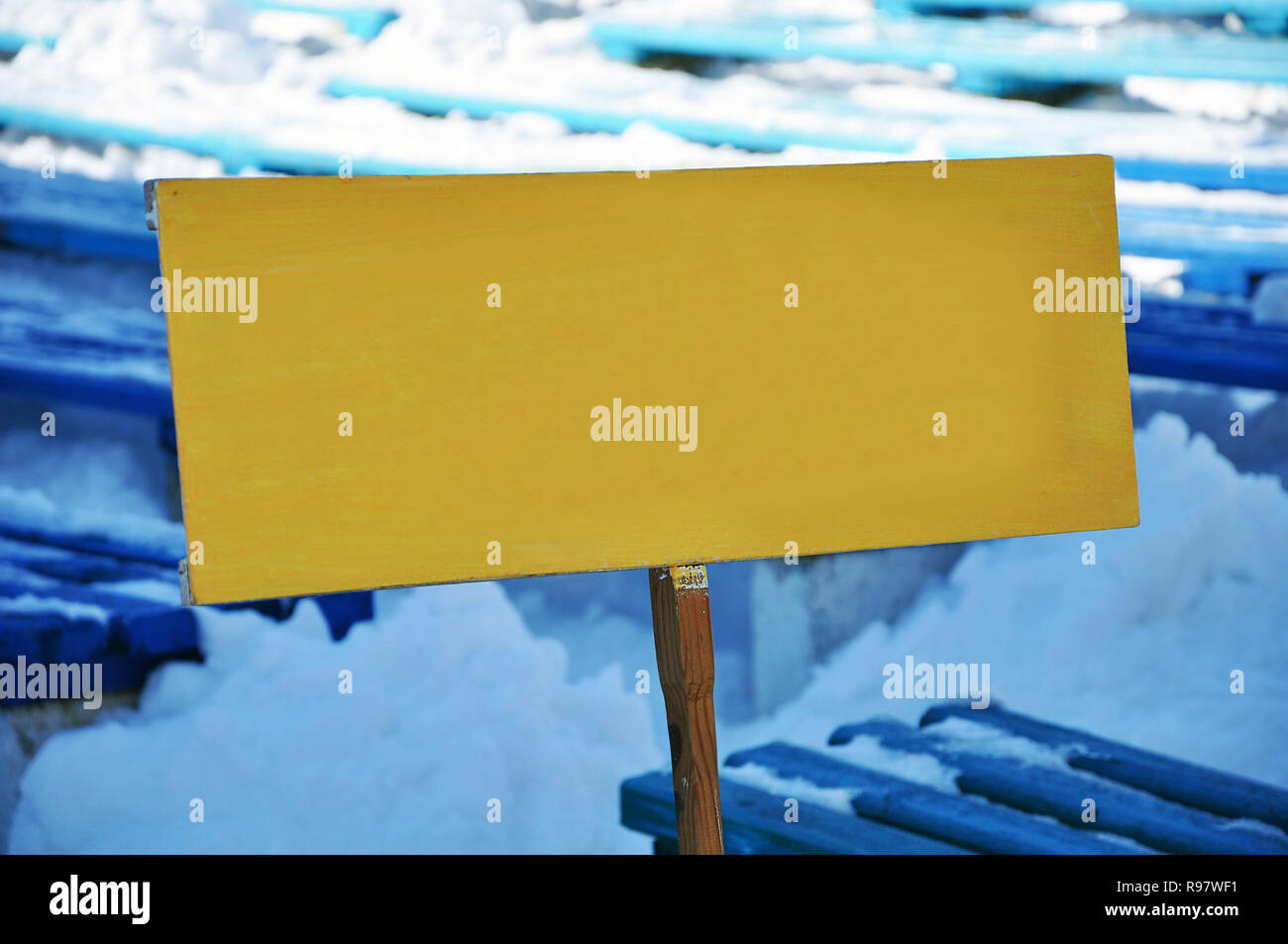 An empty yellow board on the wooden stick on the blurred Winter ...