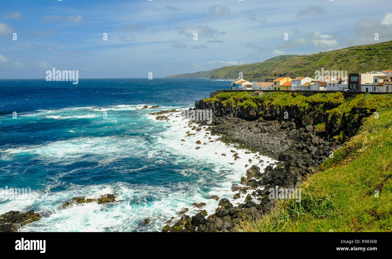 Rocky black coast of the Azores with crashing blue waves and a tiny ...
