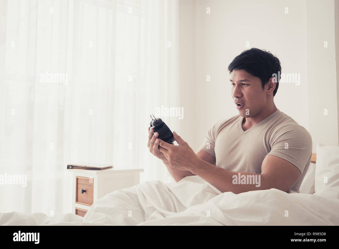 Casual man is surprise on late alarm clock time Stock Photo - Alamy