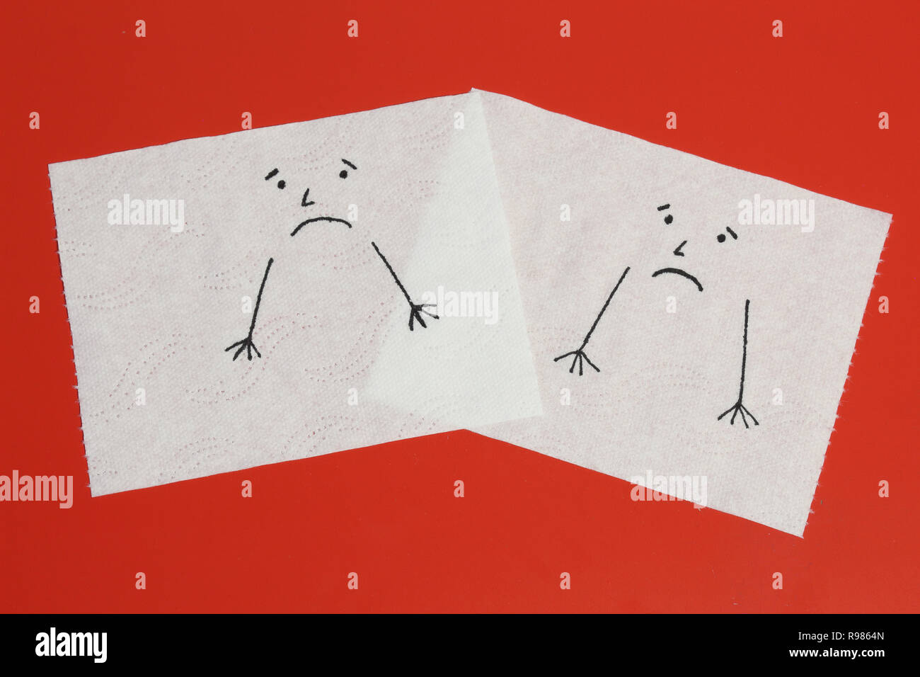 Two white toilet paper pieces sketched with sad faces close to each ...