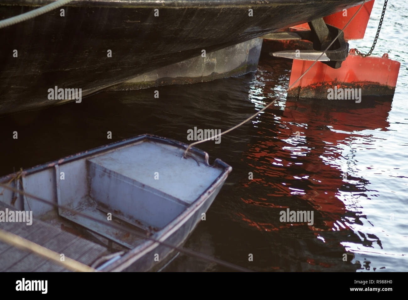 An old rowing boat made of sheet metal floats chained on a river bank ...