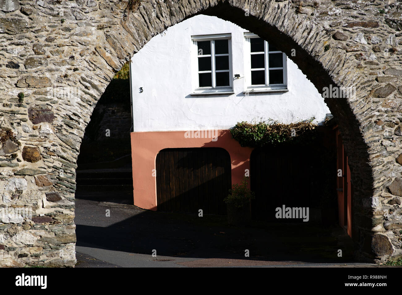 An open passage and archway of stone in a narrow lane with residential ...