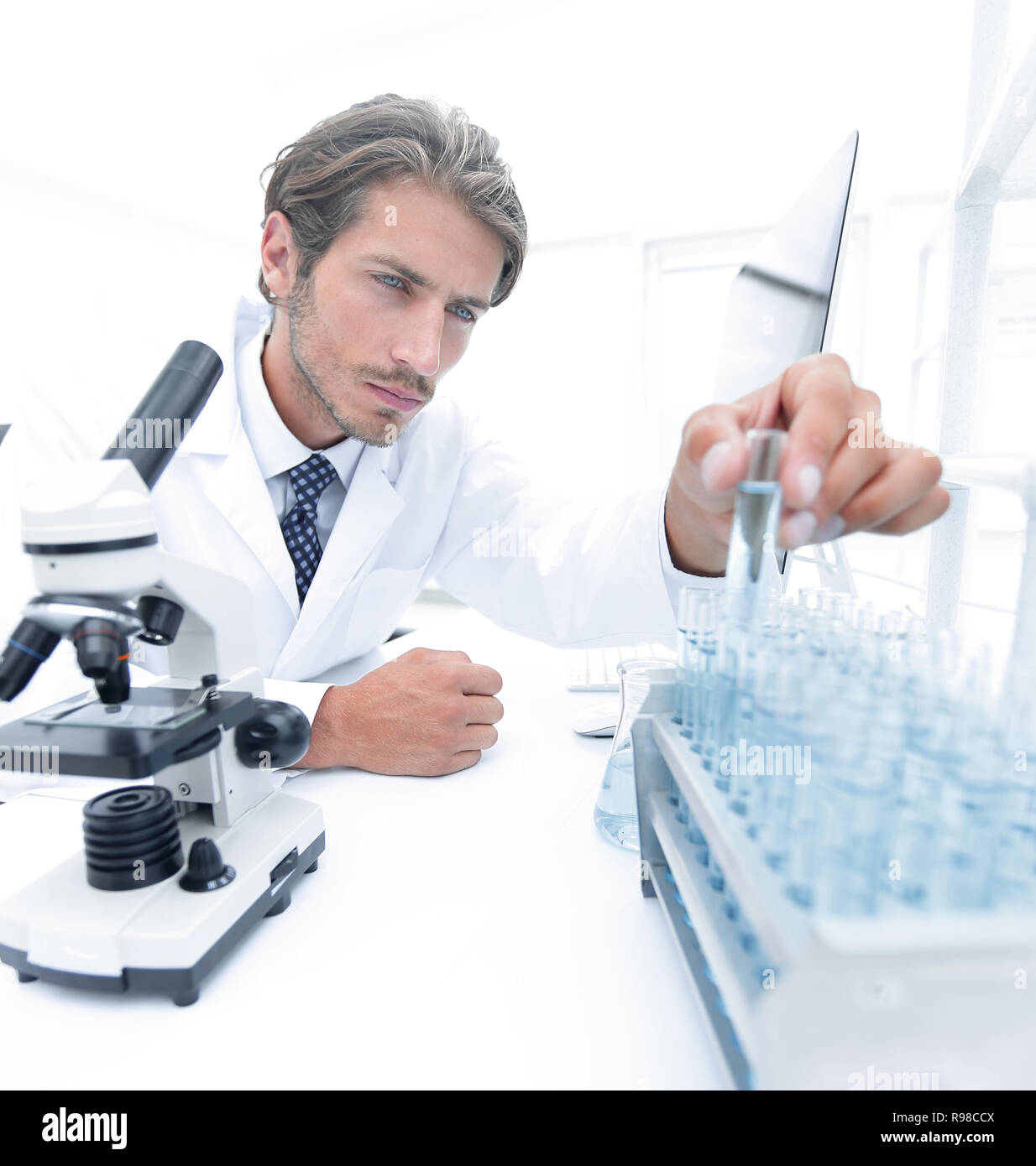 Chemist looking at test-tubes with blue liquids Stock Photo - Alamy